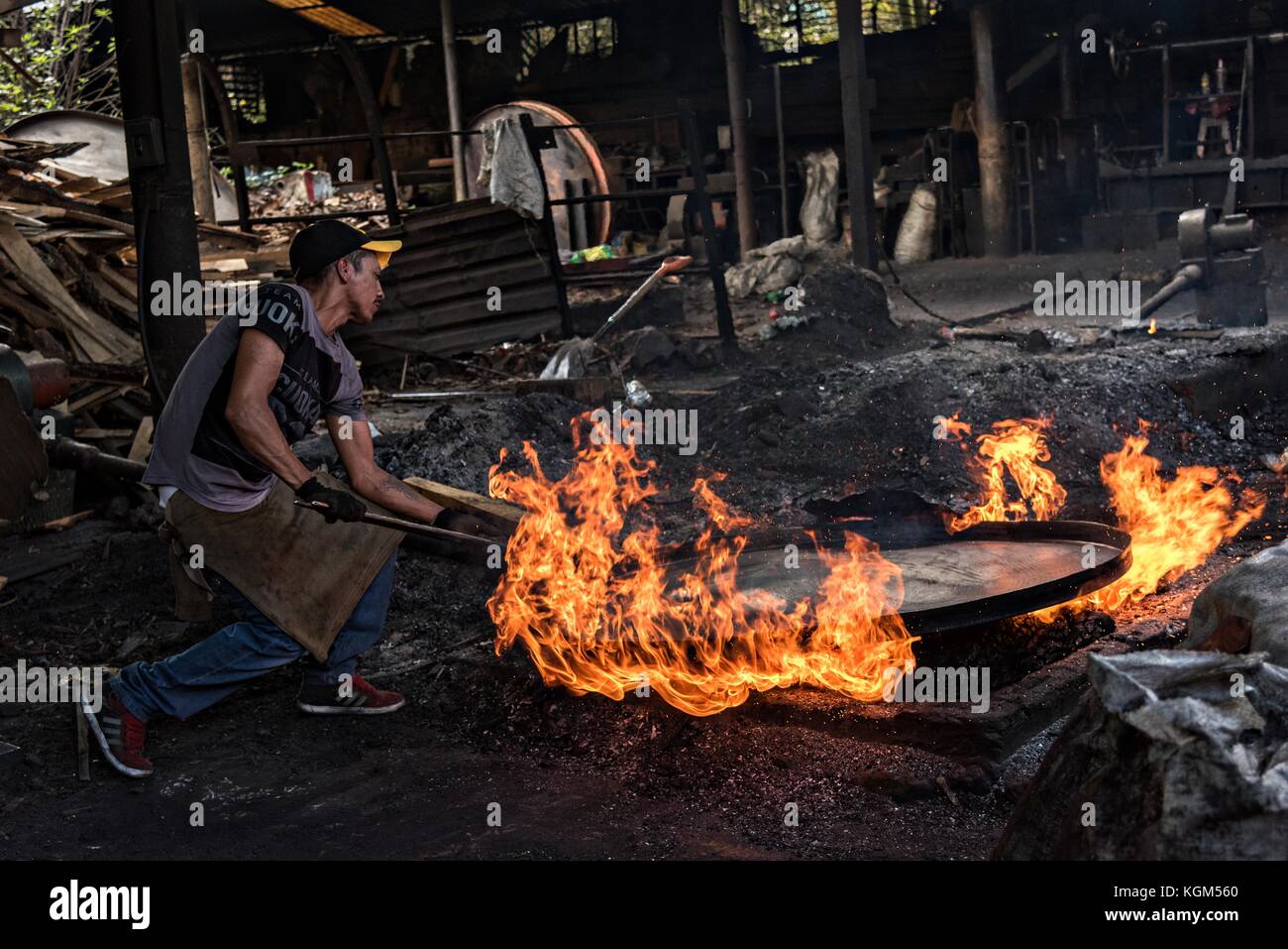 An indigenous Purepecha worker works a copper pan on an open forge to ...