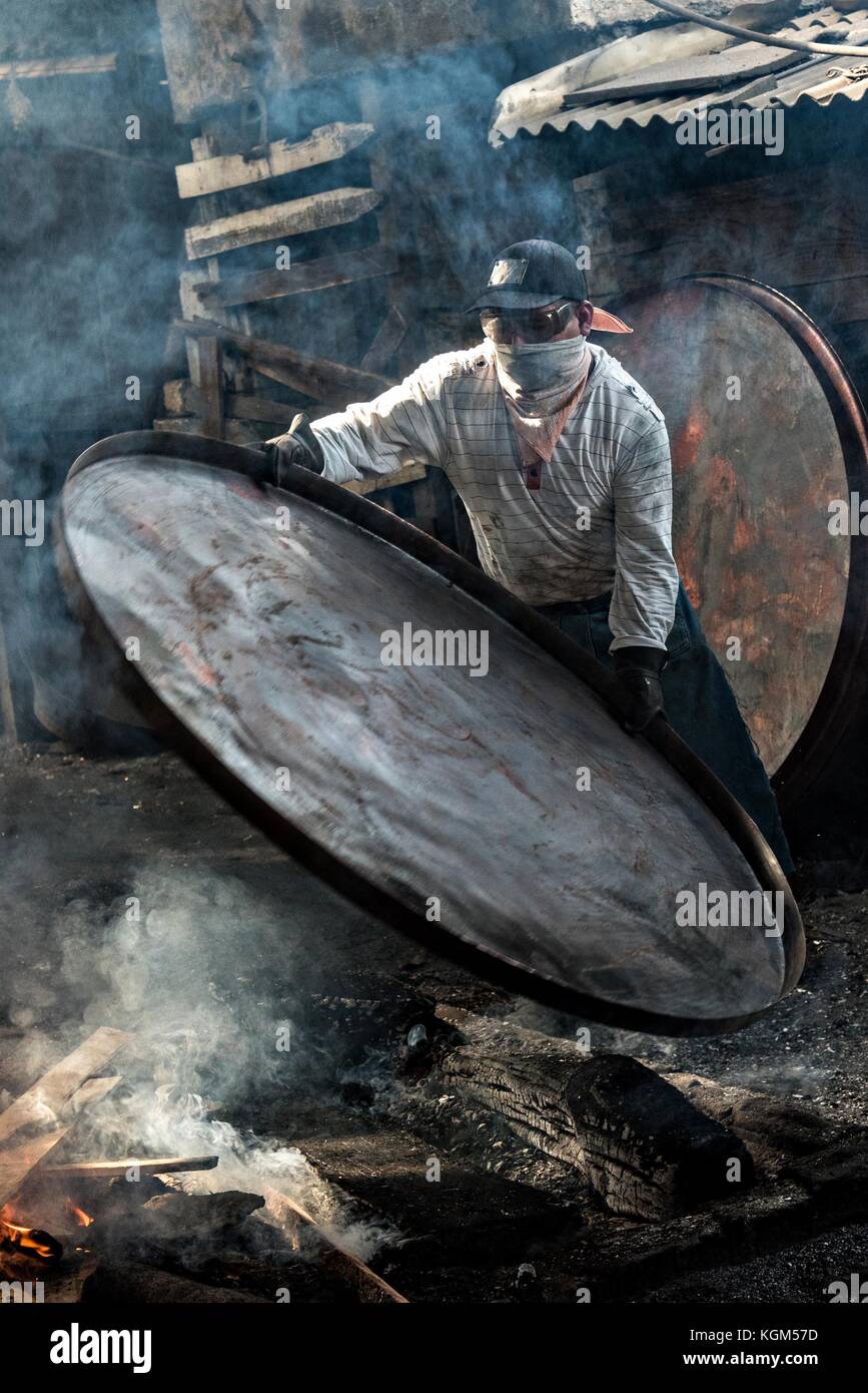 An indigenous Purepecha worker places a copper pan on an open forge to ...
