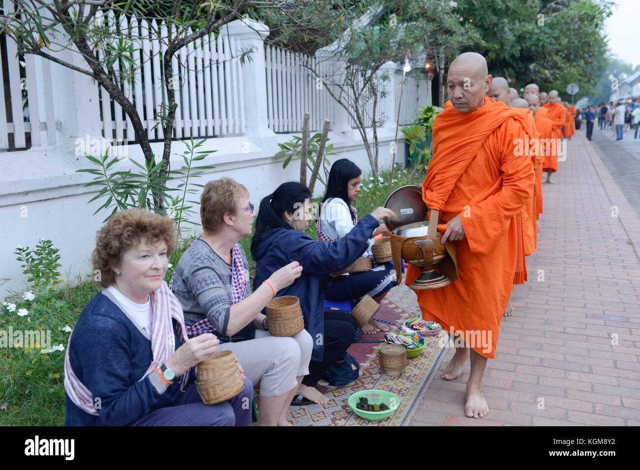 Monks going on alms round along the street in the morning of Luang ...