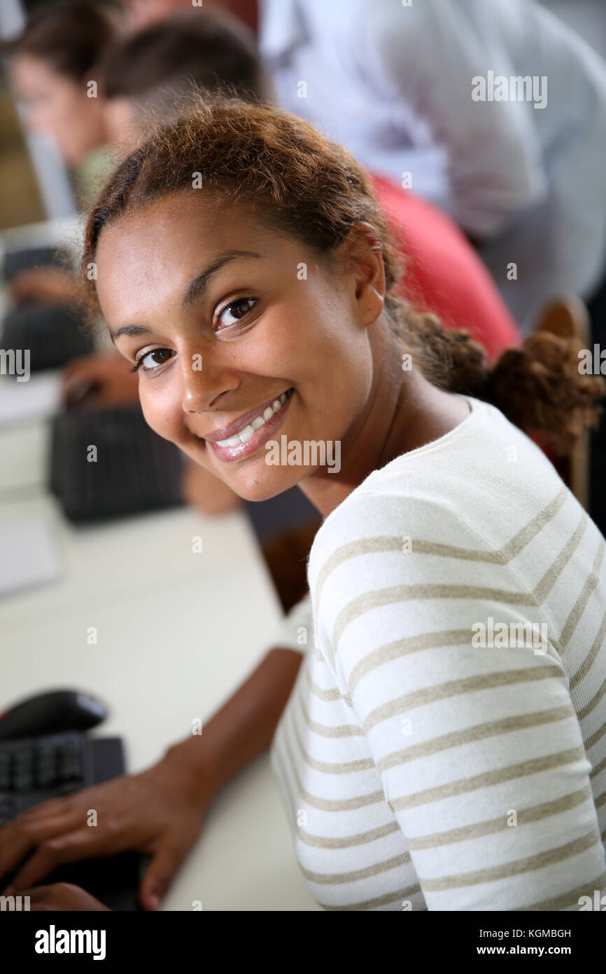 Smiling student girl sitting in computing class Stock Photo - Alamy