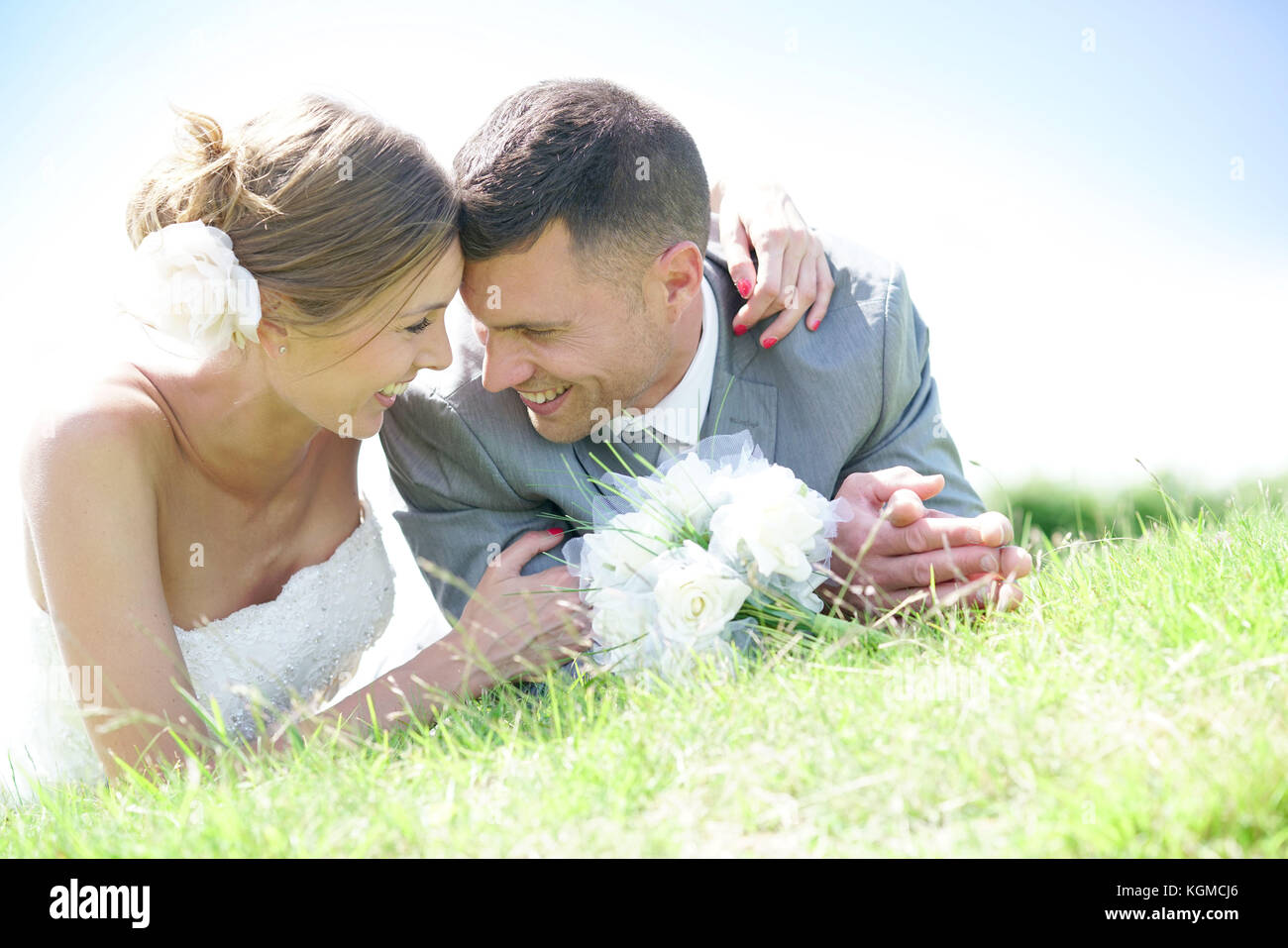Cheerful bride and groom relaxing in grass Stock Photo - Alamy
