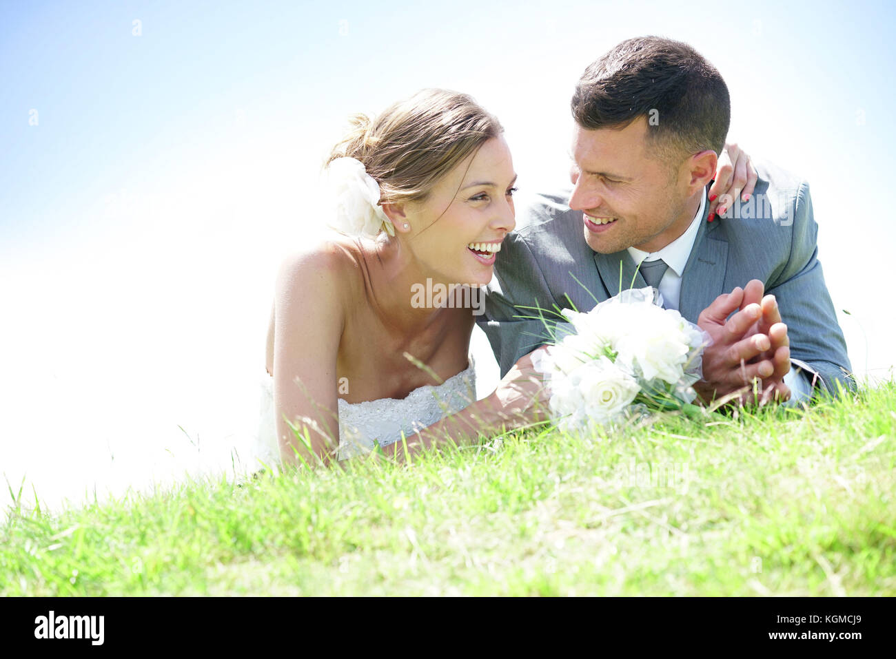 Cheerful bride and groom relaxing in grass Stock Photo - Alamy