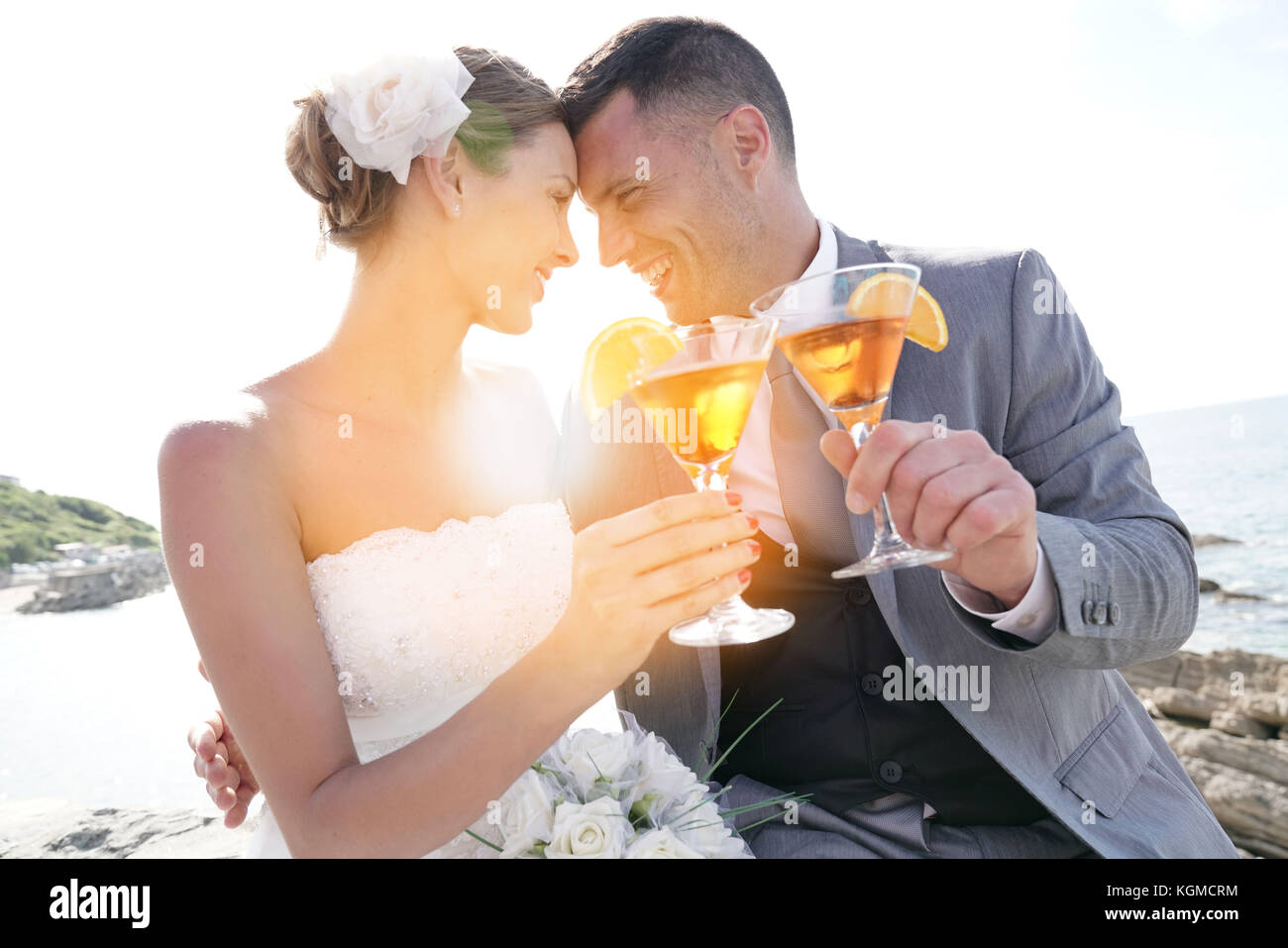 Bride and groom cheering with cocktails Stock Photo - Alamy