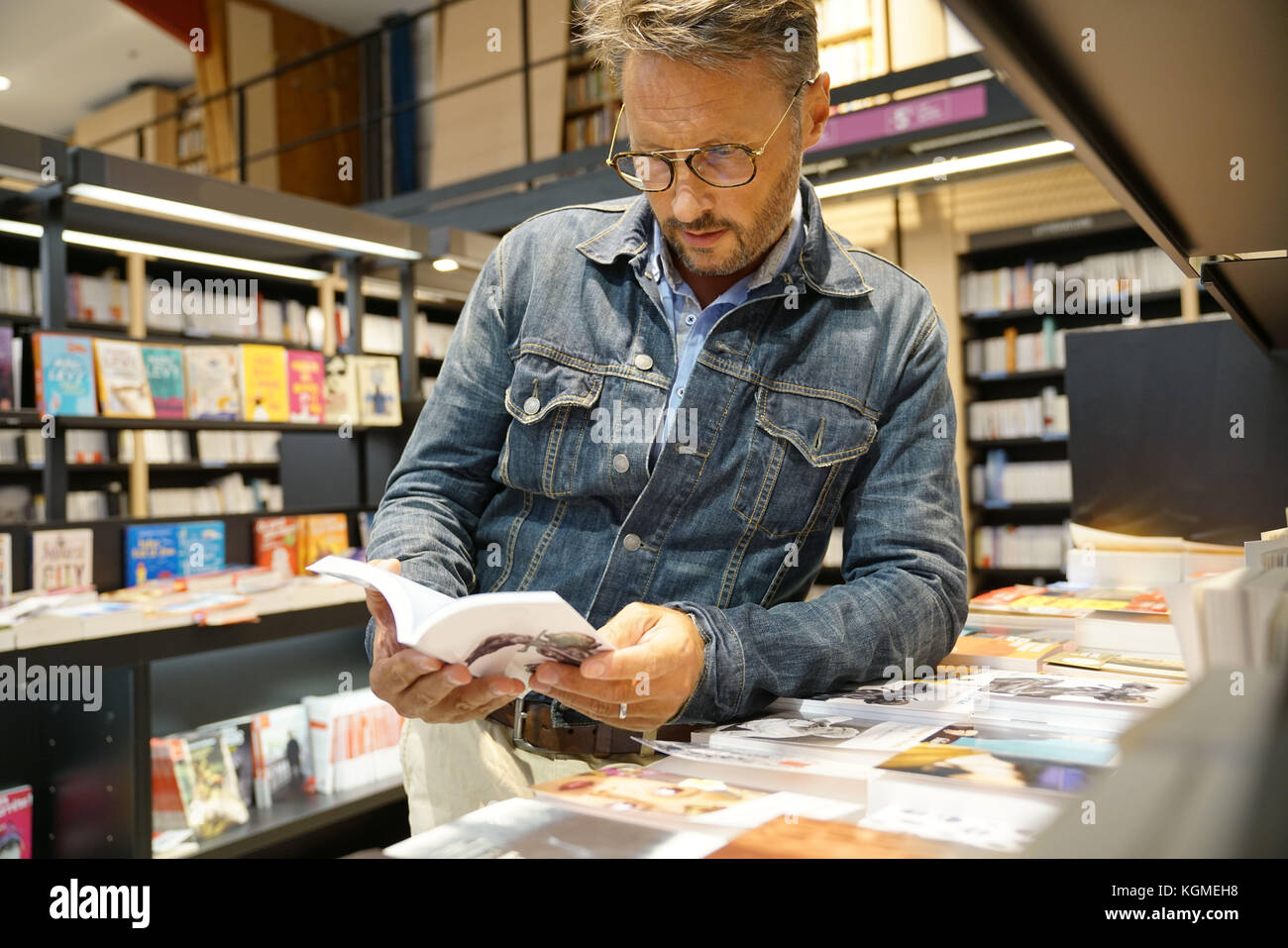 Man in bookstore looking at new books Stock Photo - Alamy
