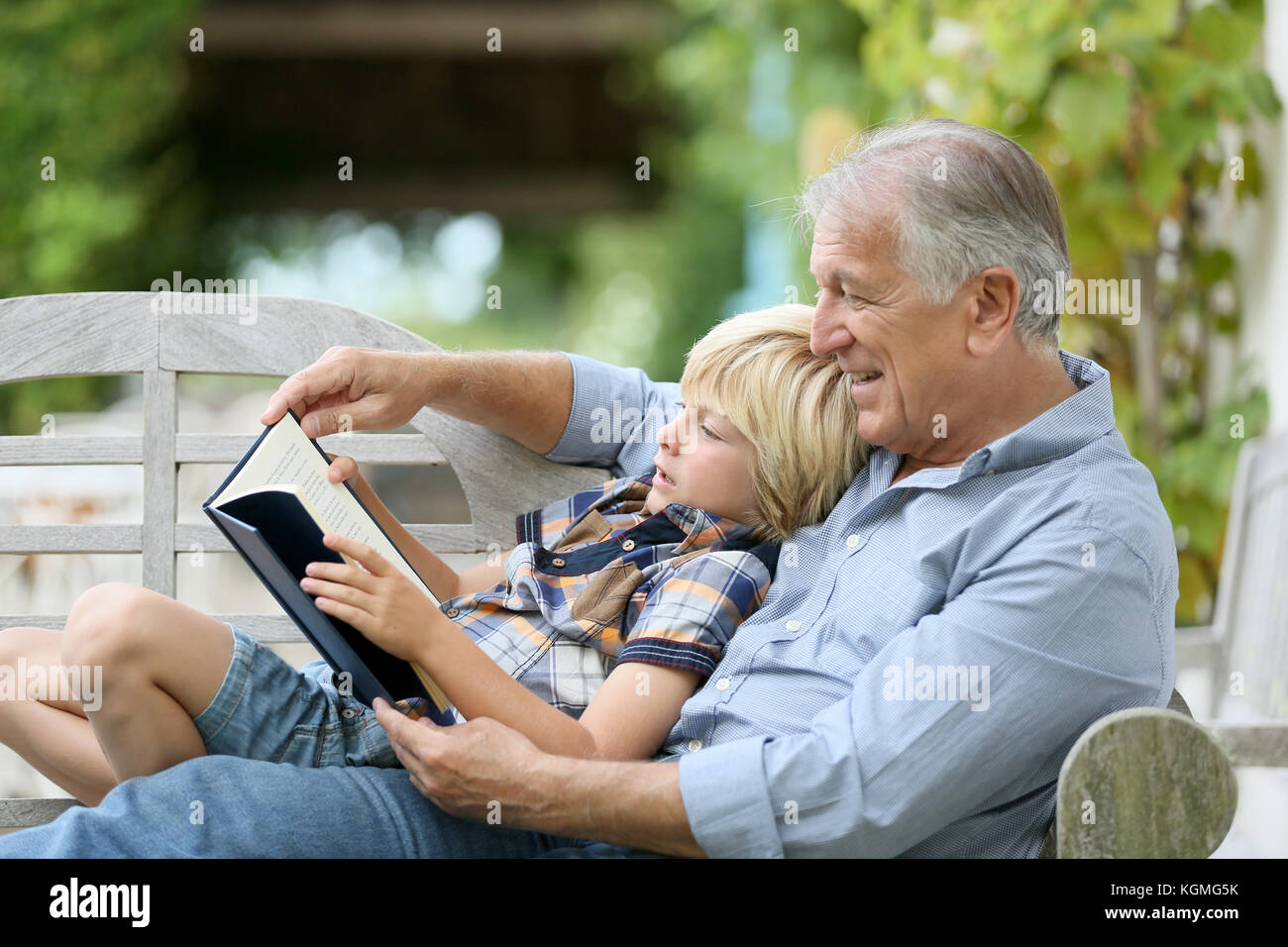 Grandfather reading book with grandson Stock Photo - Alamy