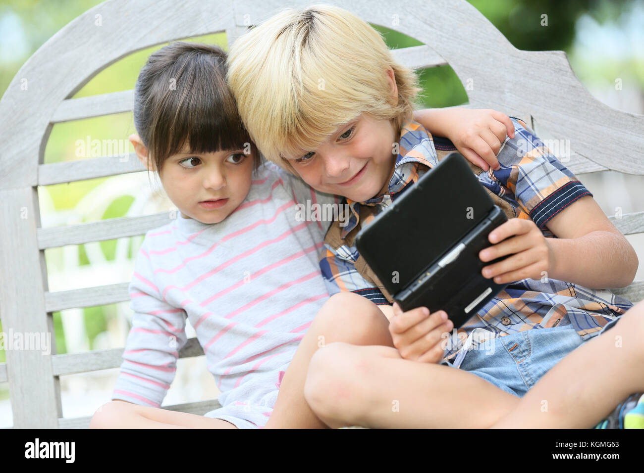 Kids sitting on outdoor bench and playing video games Stock Photo - Alamy