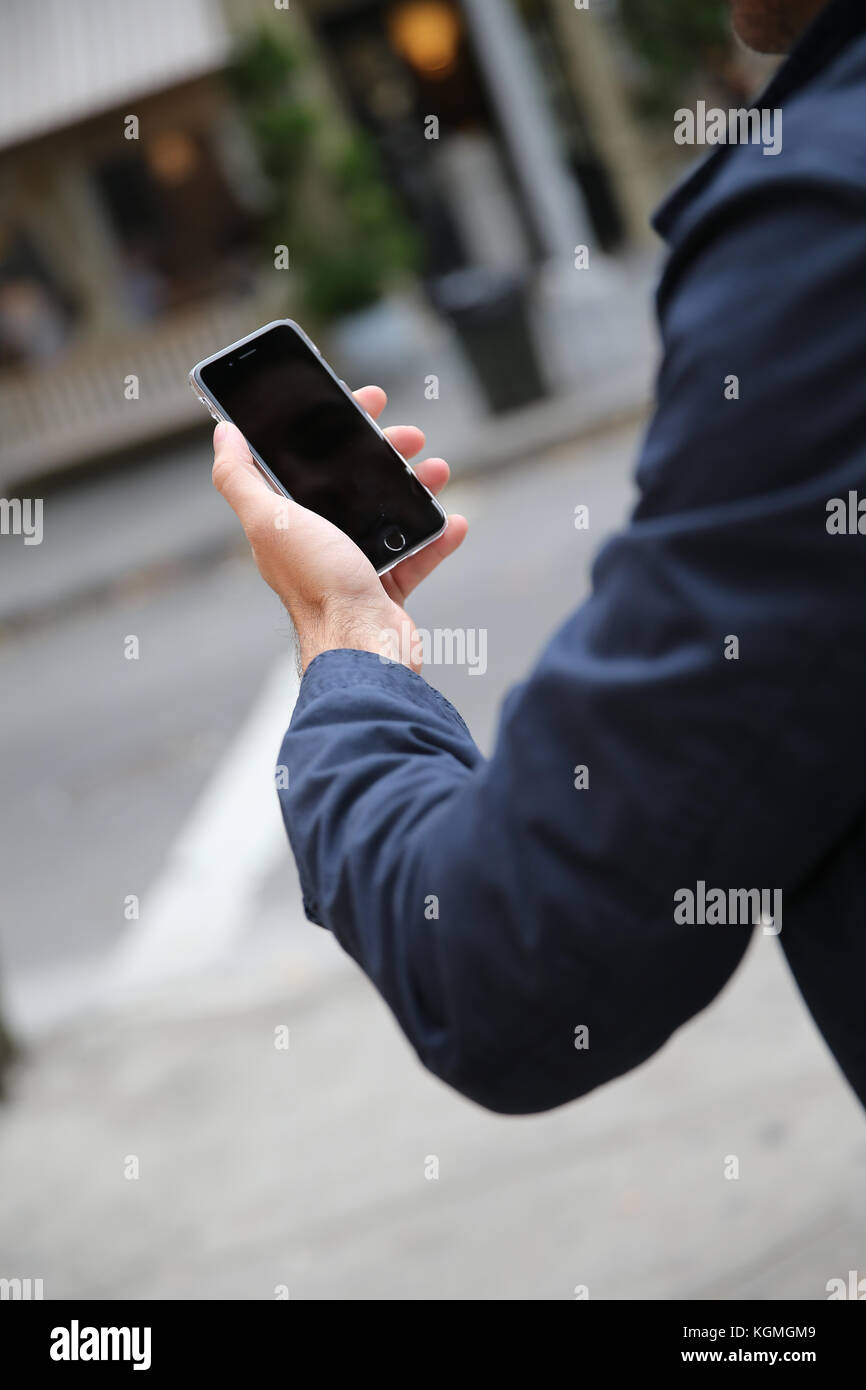 Man in city street showing smartphone screen Stock Photo - Alamy