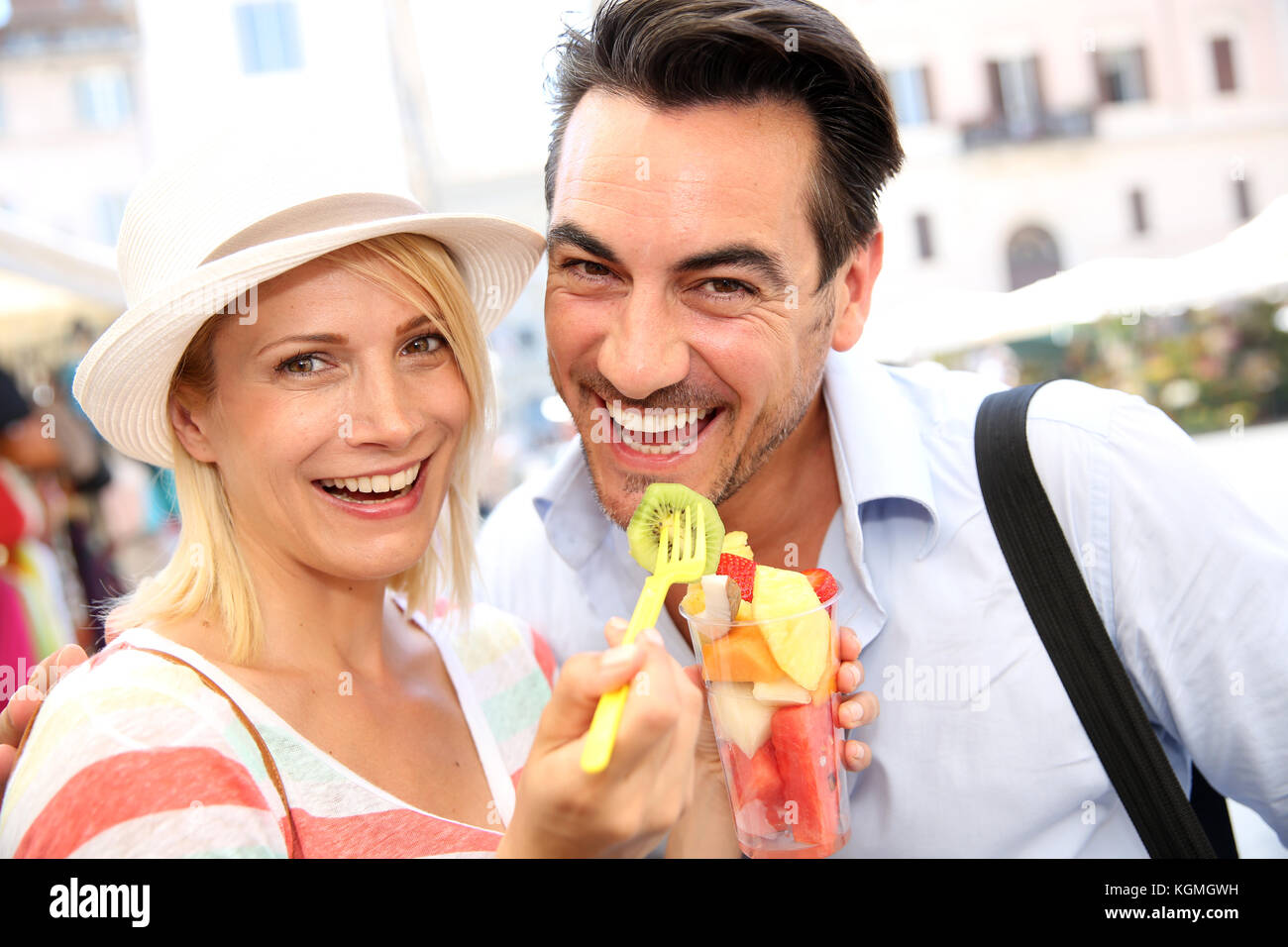 Couple of tourists having fun eating fresh fruits Stock Photo - Alamy
