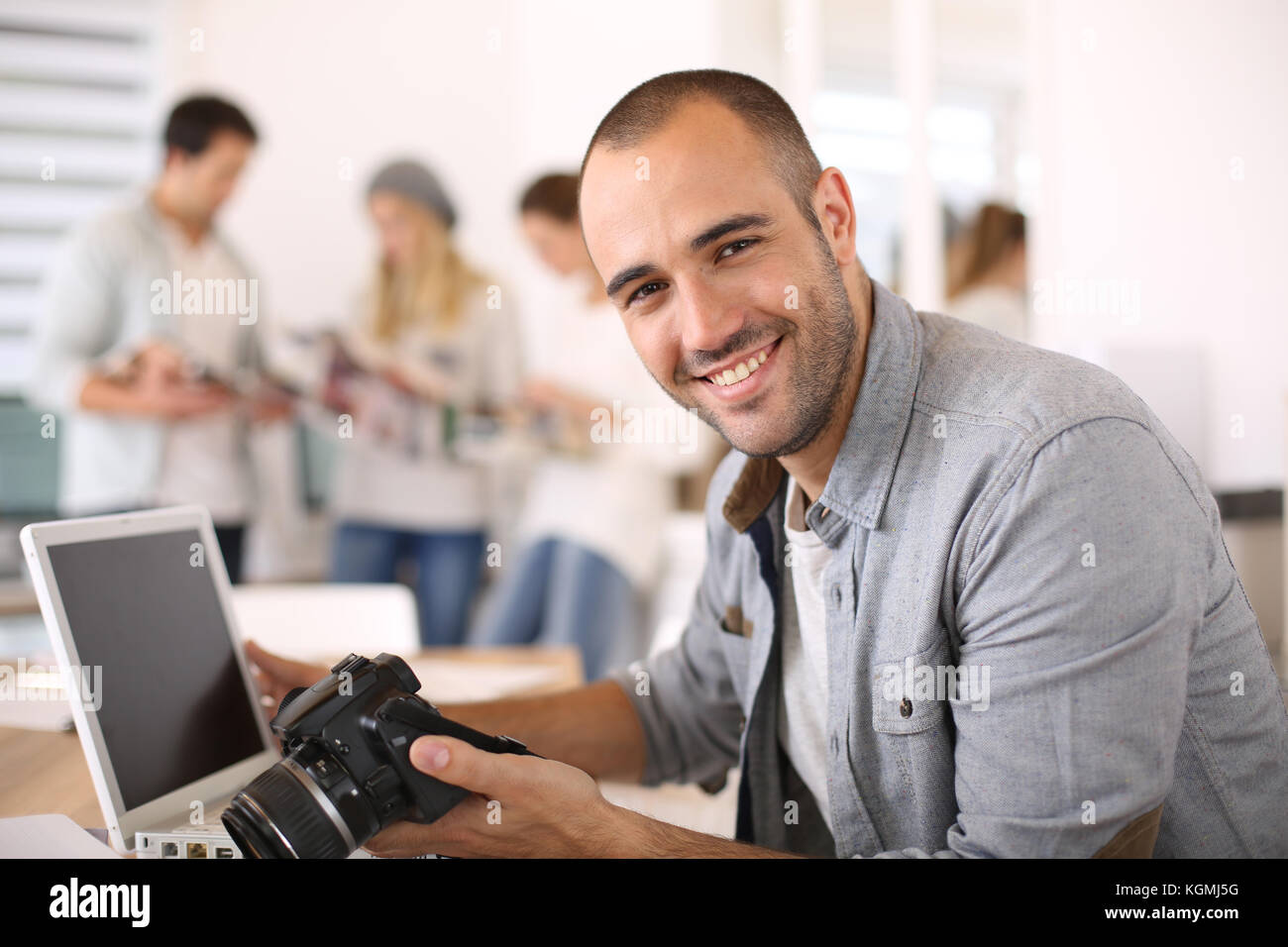 CHeerful reporter working in office on laptop Stock Photo - Alamy