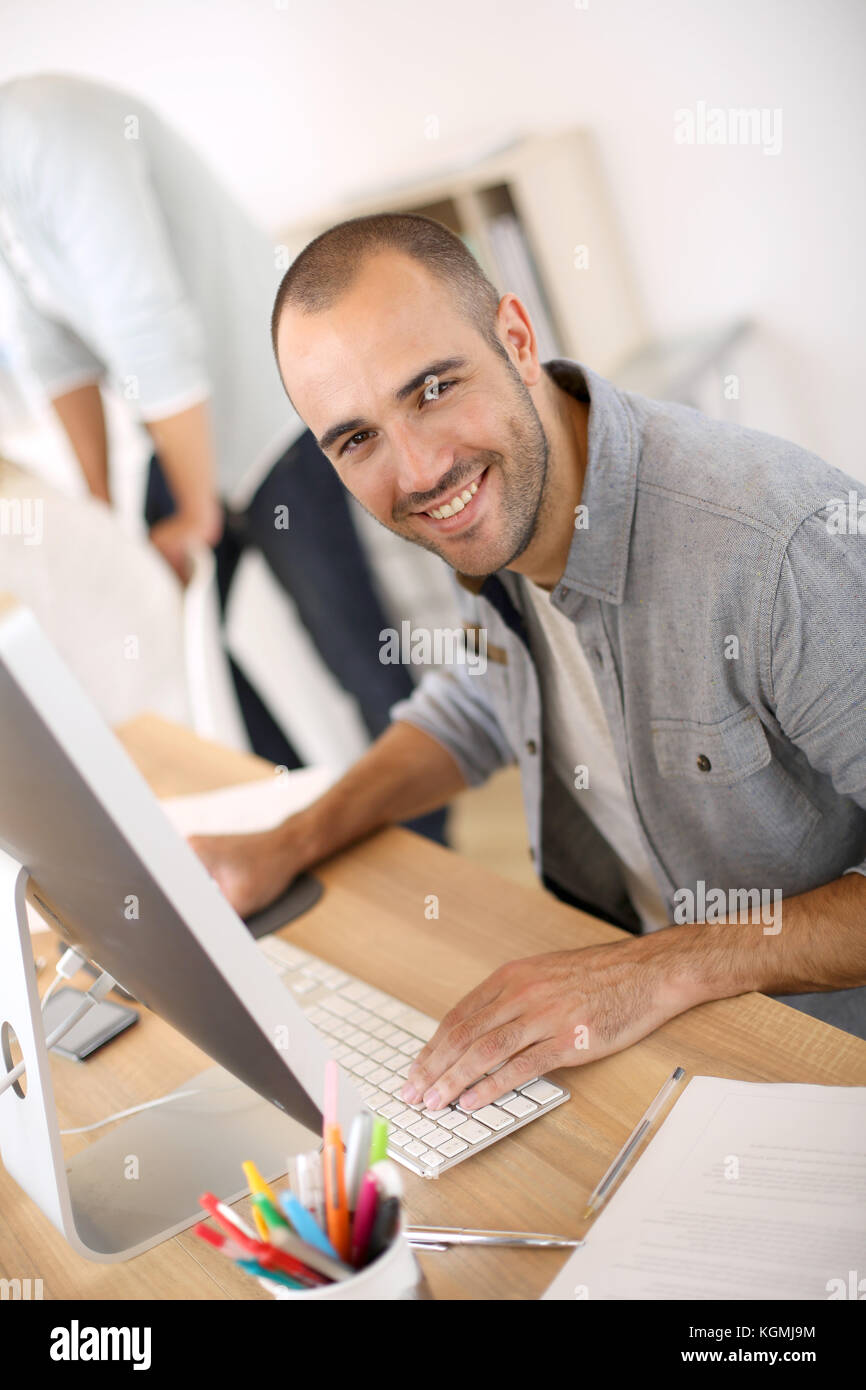 Cheerful guy sitting in front of desktop computer Stock Photo - Alamy