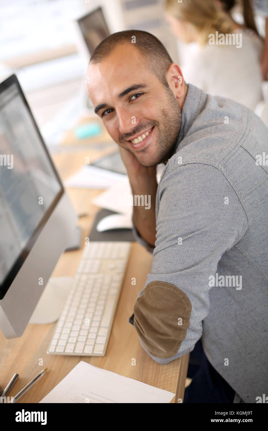 Cheerful guy sitting in front of desktop computer Stock Photo - Alamy