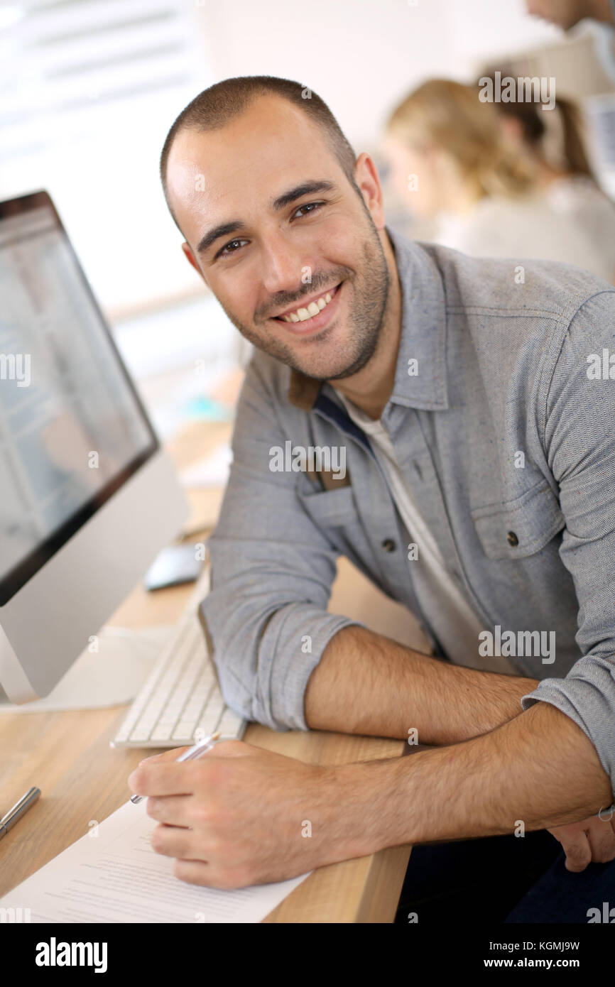 Cheerful guy sitting in front of desktop computer Stock Photo - Alamy