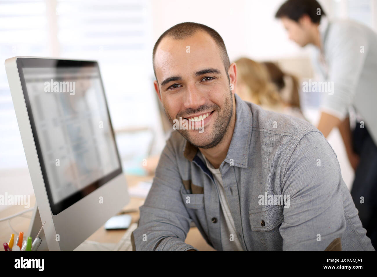 Cheerful guy sitting in front of desktop computer Stock Photo - Alamy