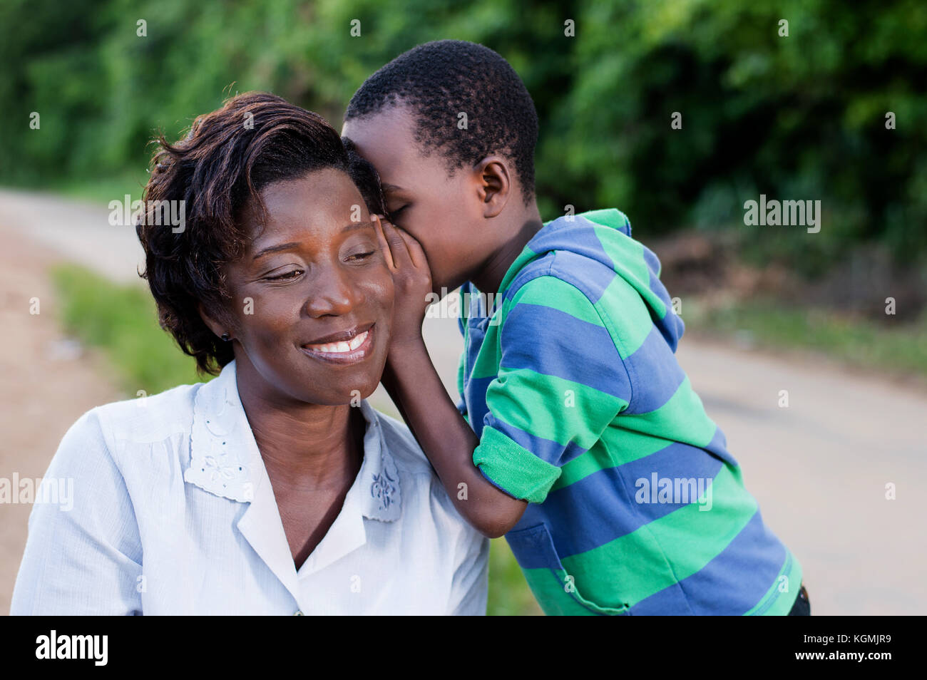 child talking secretly to his mother's ear in campaign Stock Photo - Alamy