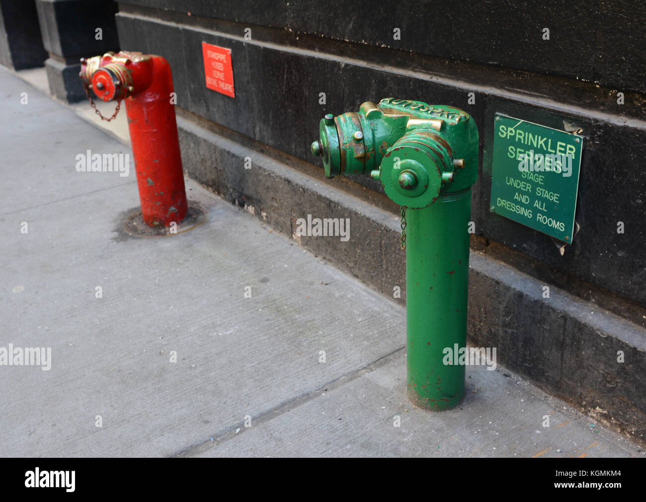 Red and green siamese standpipes on a sidewalk with theatre-related ...