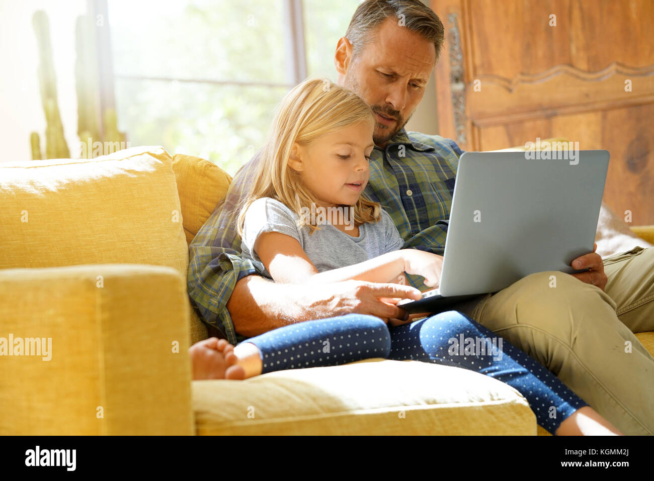 Daddy with little girl using laptop, sitting on couch Stock Photo - Alamy