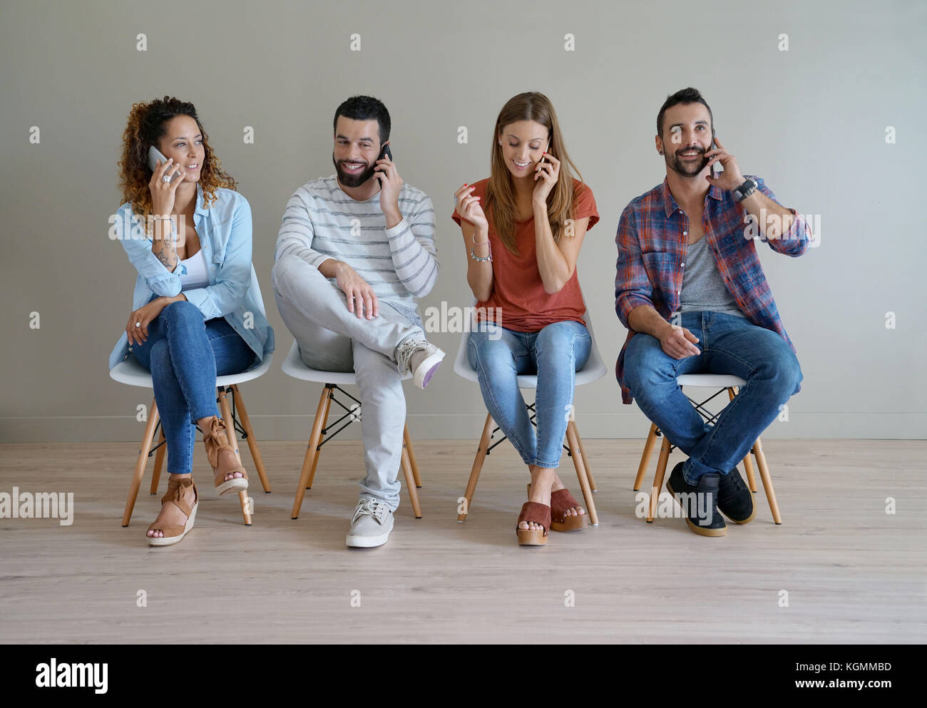 Young people in waiting room talking on phone Stock Photo - Alamy