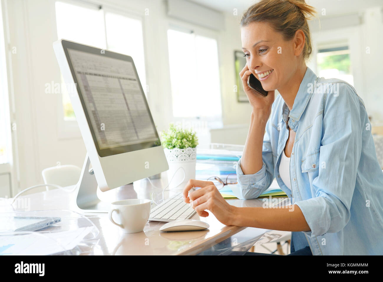Office worker talking on phone in front of desktop Stock Photo - Alamy