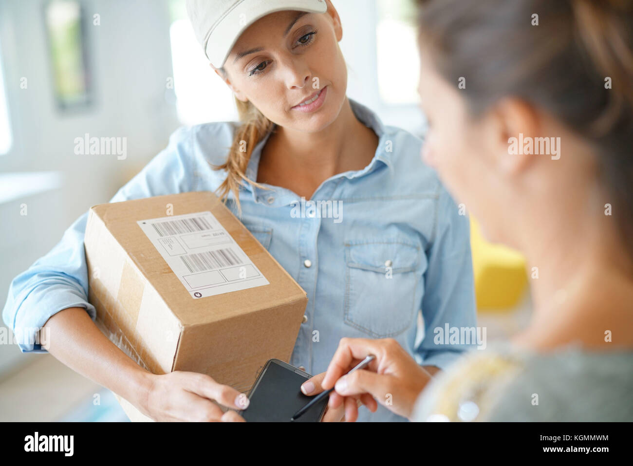 Delivery woman handing package to customer against signature Stock ...