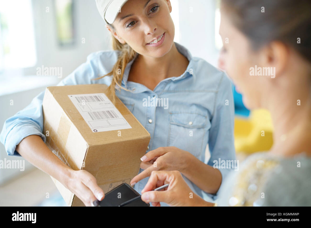 Delivery woman handing package to customer against signature Stock ...