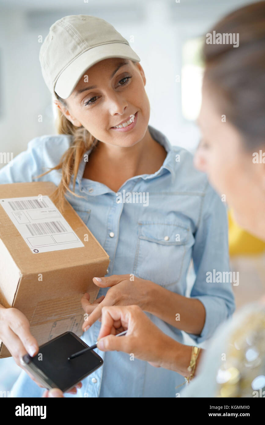 Delivery woman handing package to customer against signature Stock ...