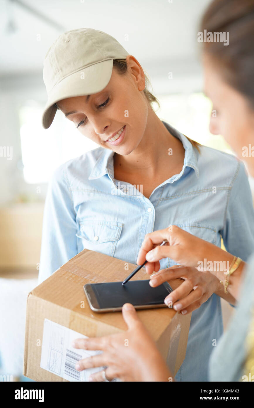 Delivery woman handing package to customer against signature Stock ...