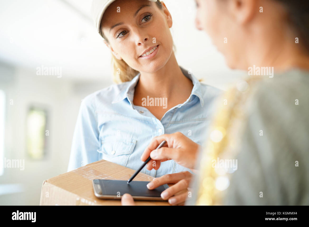 Delivery woman handing package to customer against signature Stock ...