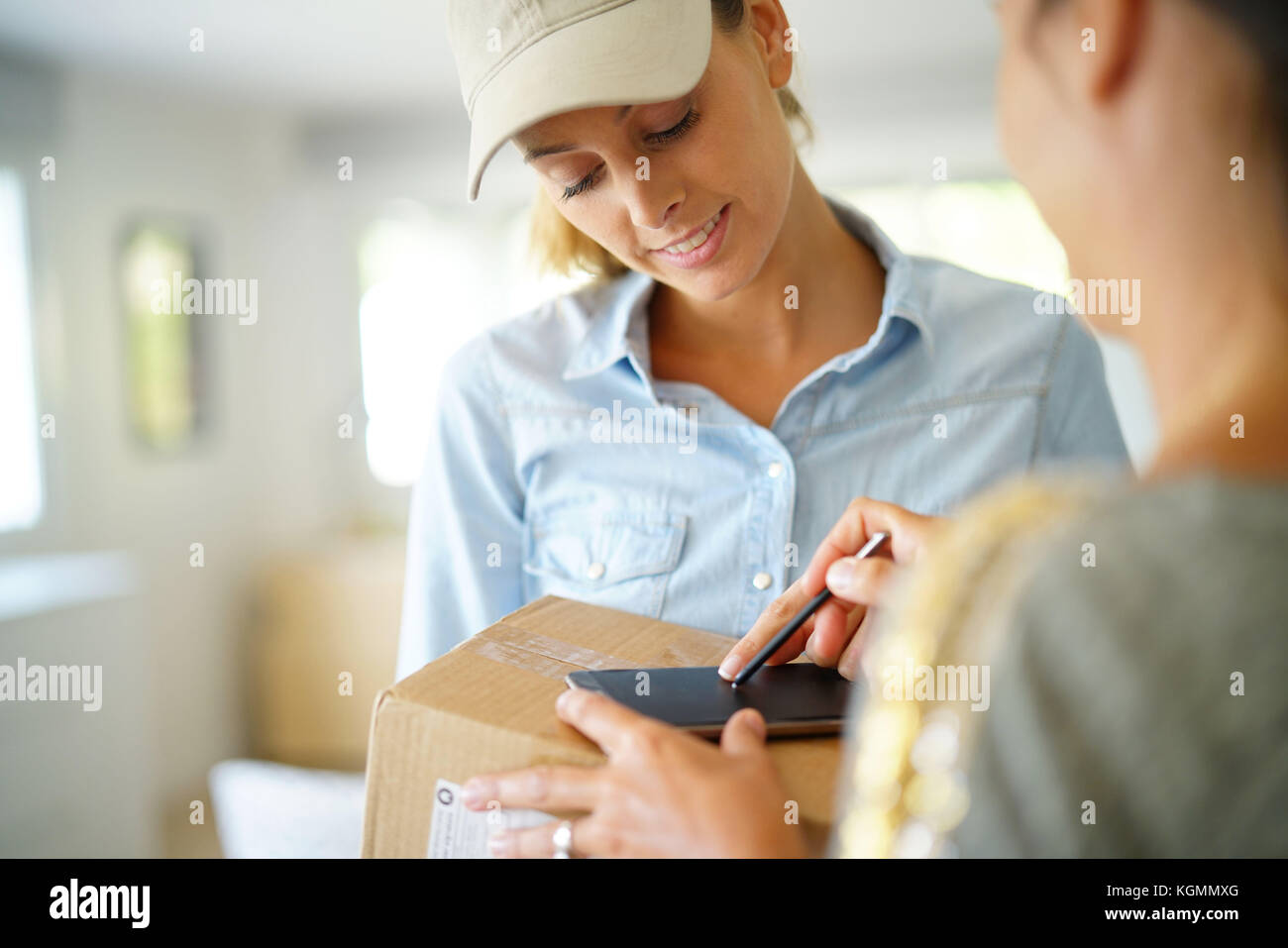 Delivery woman handing package to customer against signature Stock ...