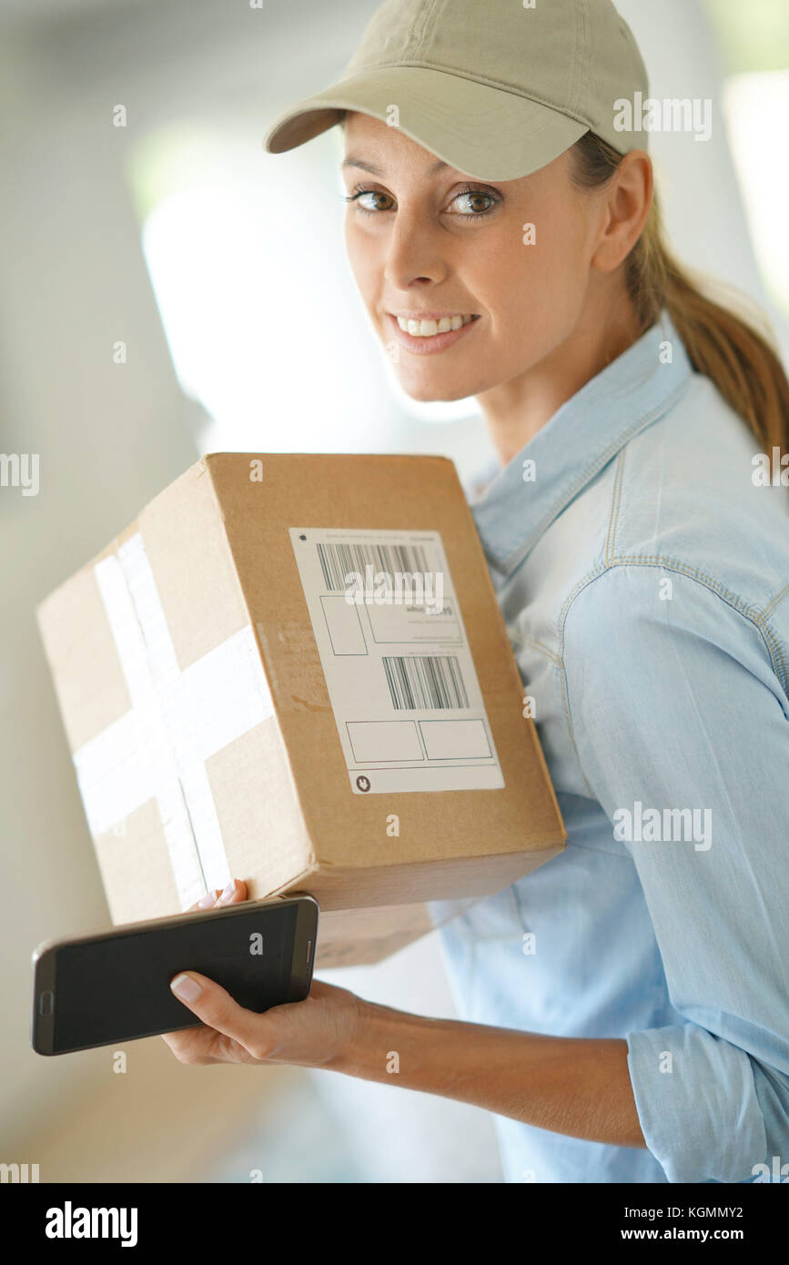 Portrait of smiling delivery woman holding package Stock Photo - Alamy