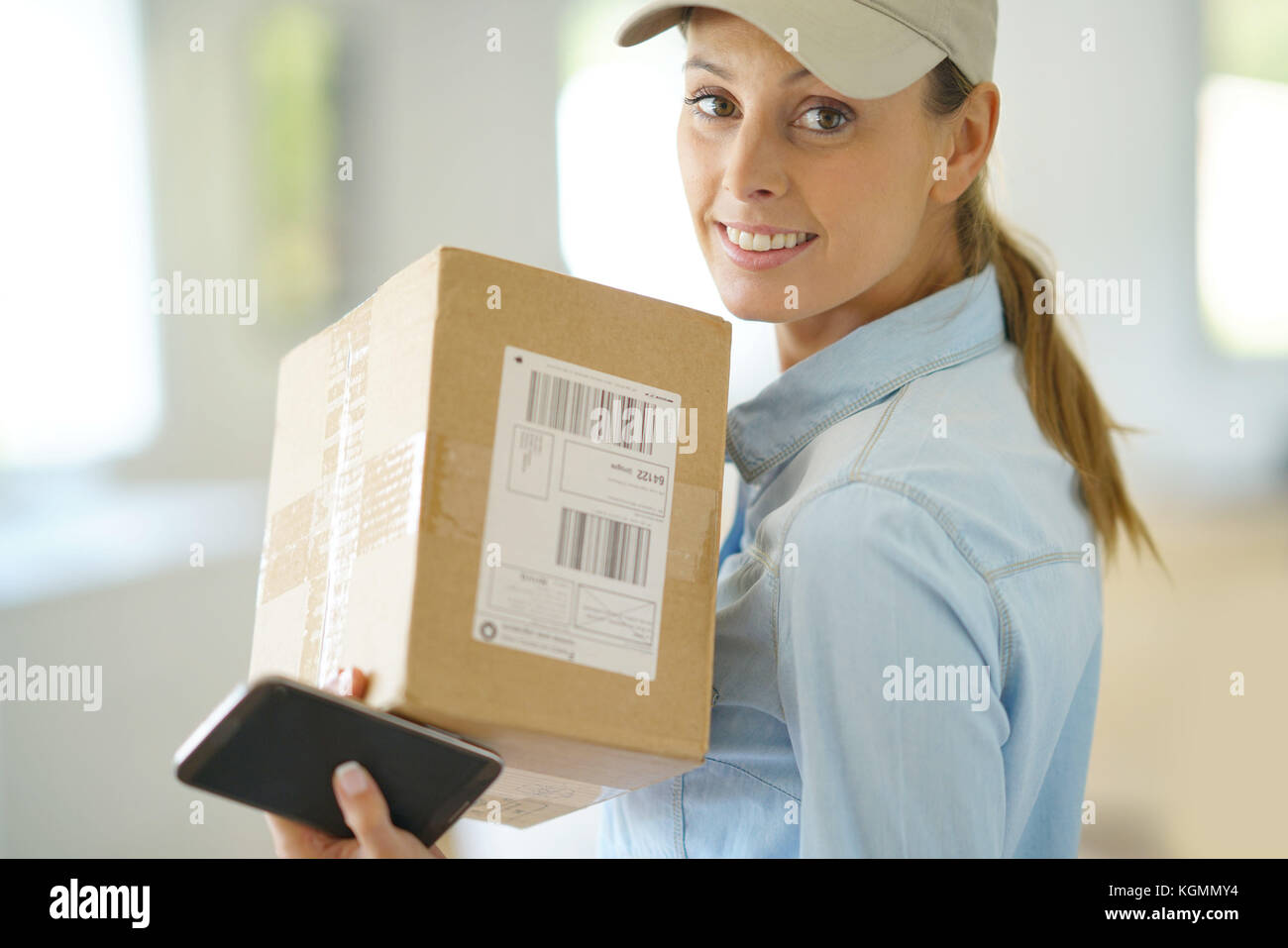 Portrait of smiling delivery woman holding package Stock Photo - Alamy