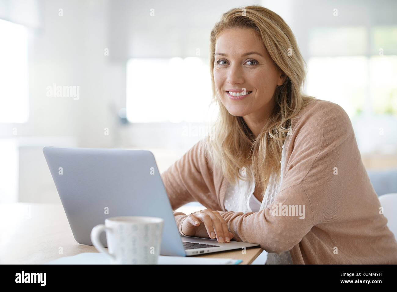 Attractive blond woman working on laptop computer at home Stock Photo ...