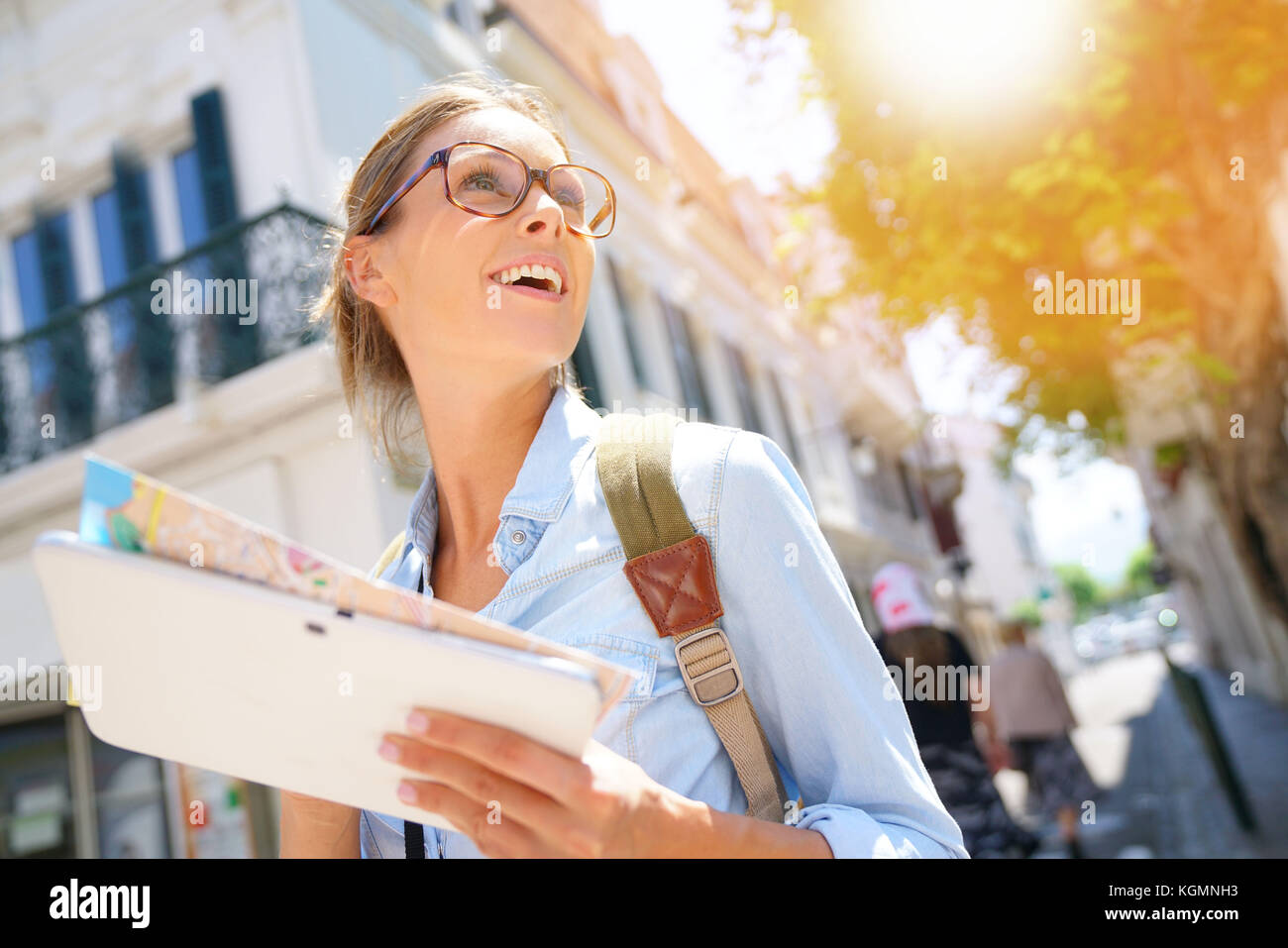 Happy tourist girl reading map and using tablet in the street Stock ...