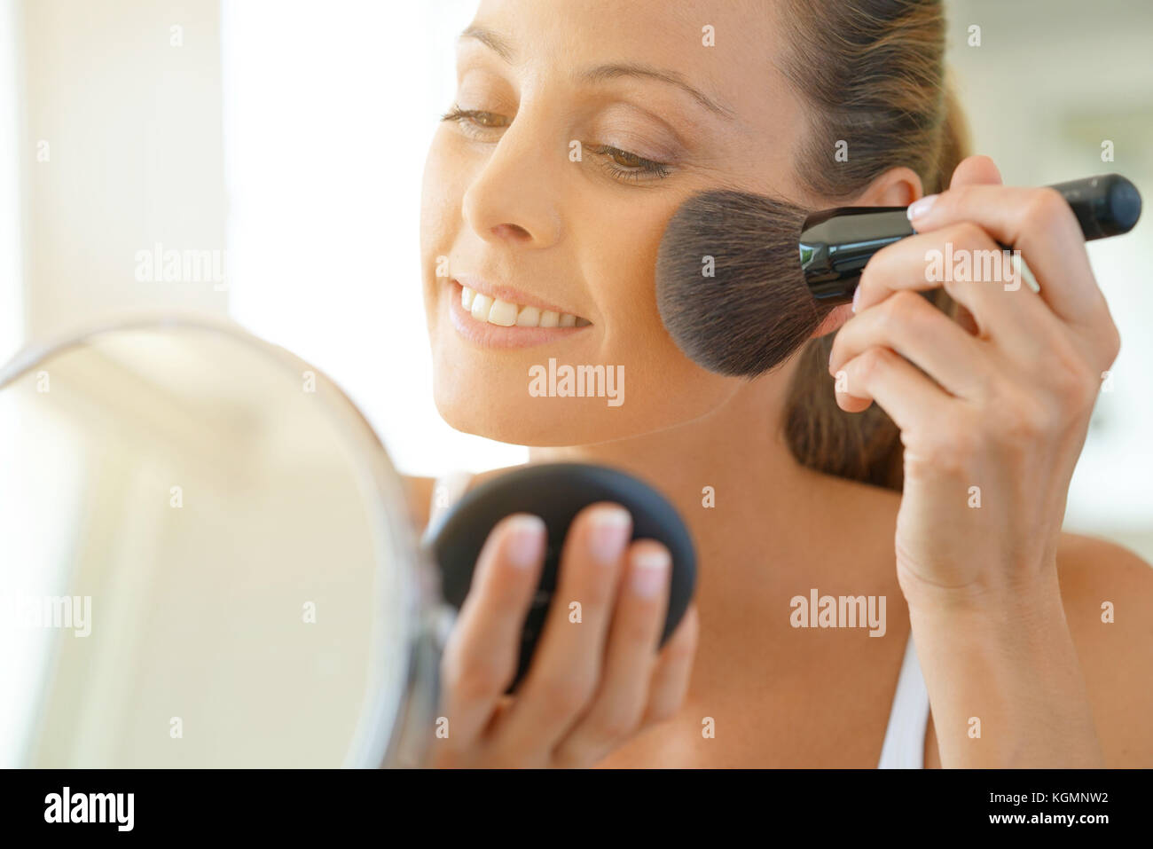 Portrait of beautiful woman putting makeup on Stock Photo - Alamy