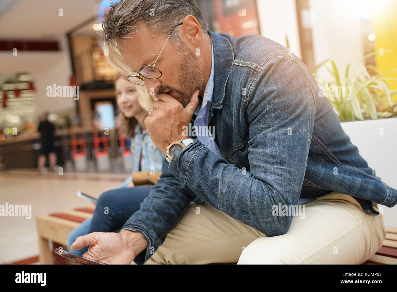 Man sitting on public bench in shopping mall Stock Photo - Alamy