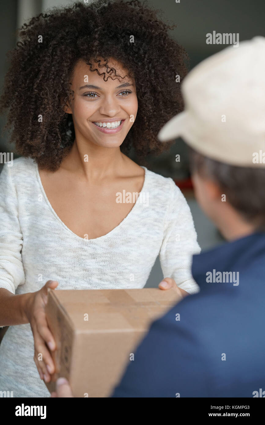 Mixed race woman receiving package from delivery man Stock Photo - Alamy