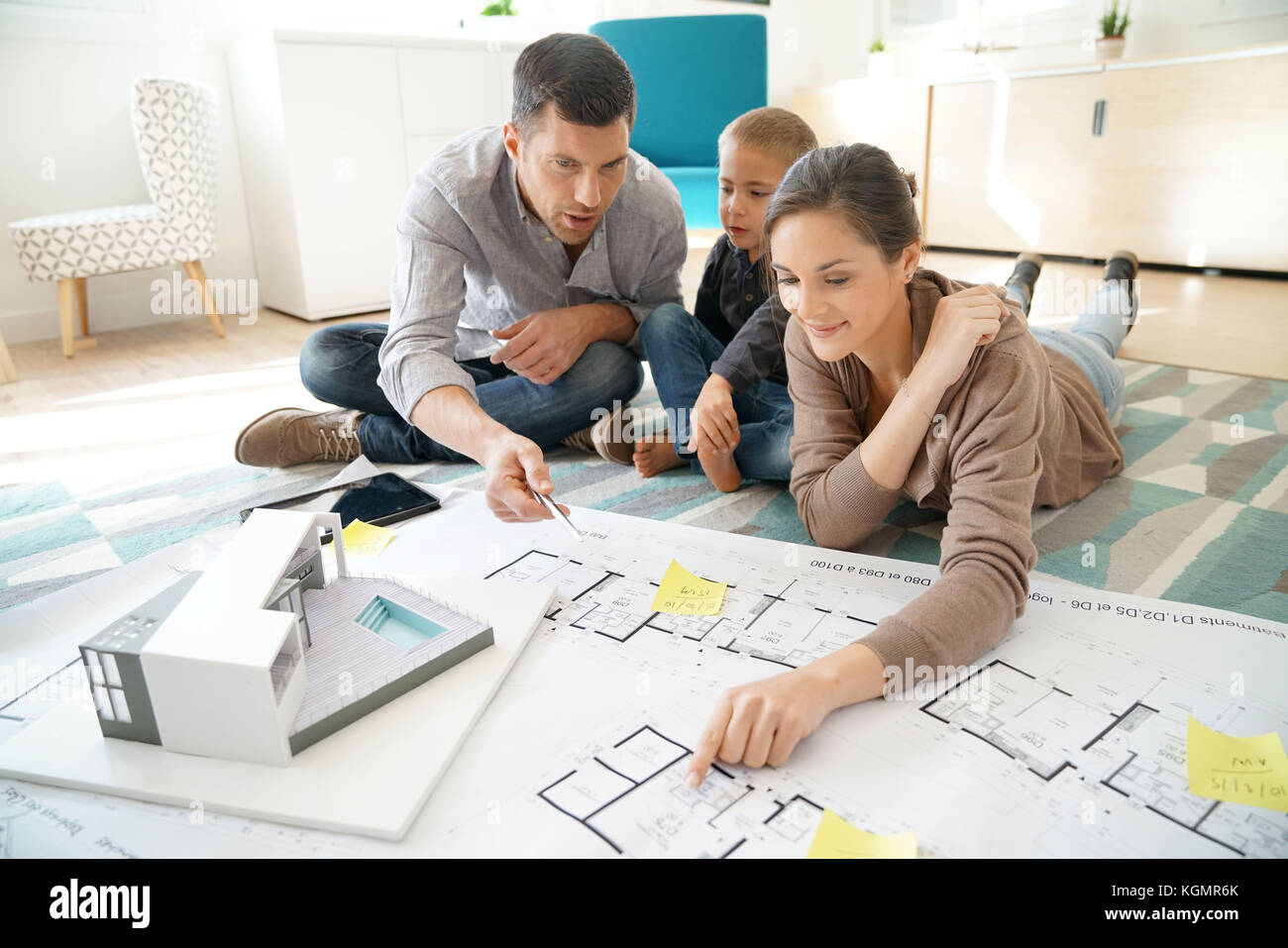 Family at home looking at future house blueprint and model Stock Photo ...