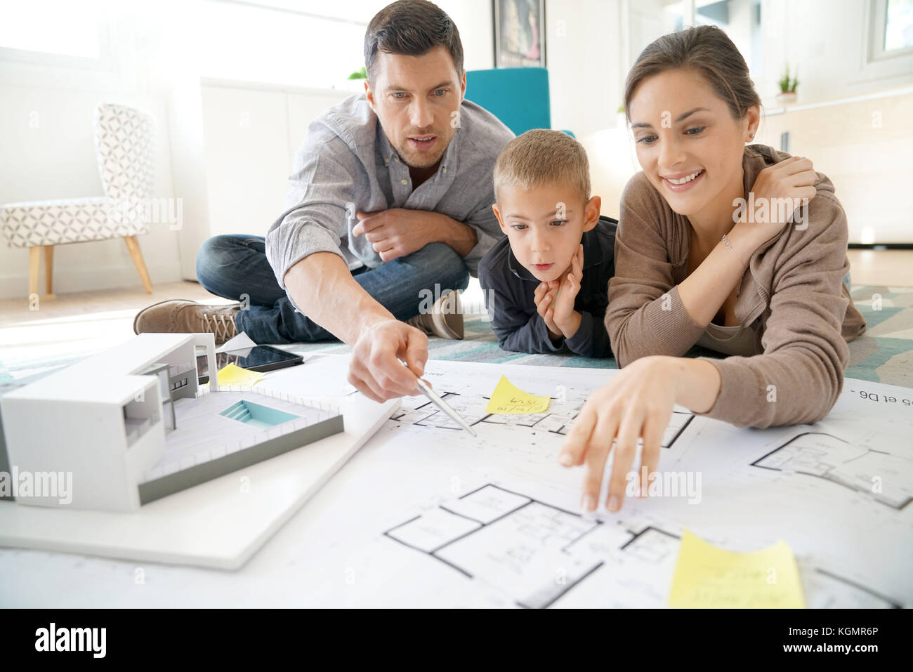 Family at home looking at future house blueprint and model Stock Photo ...