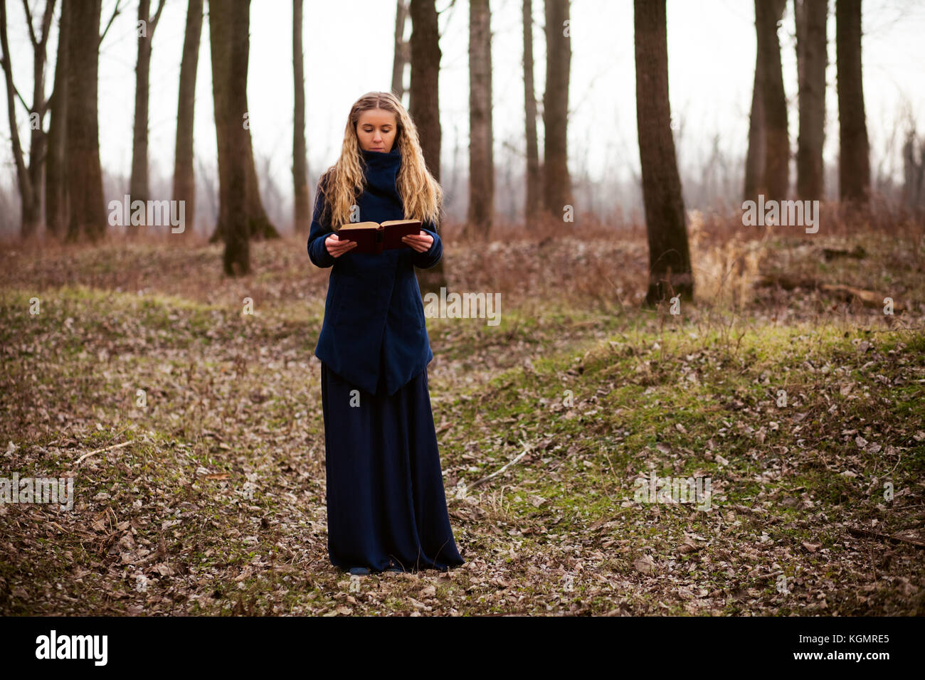 Woman standing lonely in forest in wintertime and reading a book Stock ...