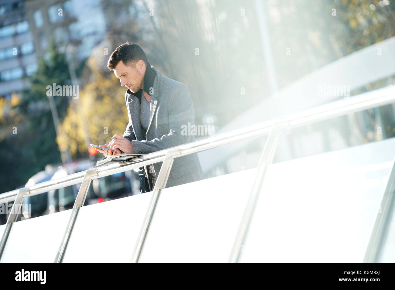 Businessman waiting outside the office, using agenda Stock Photo - Alamy