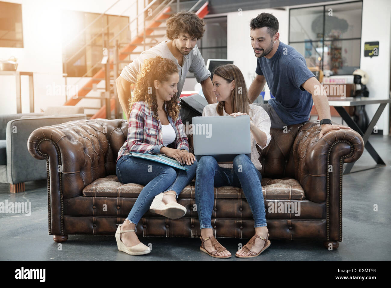 Group of trendy people sitting on couch in loft Stock Photo - Alamy