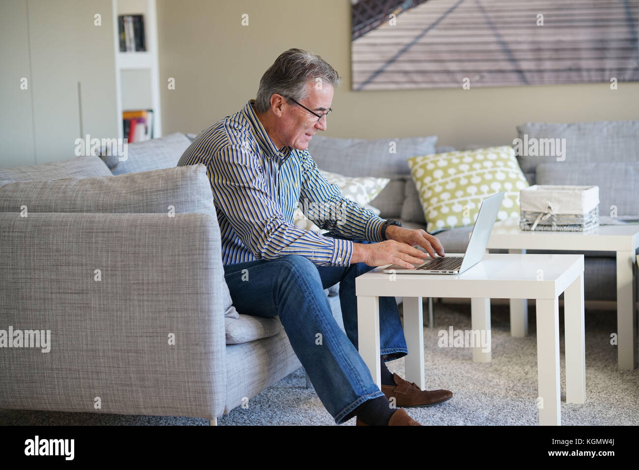 Senior man in living-room using laptop computer Stock Photo - Alamy