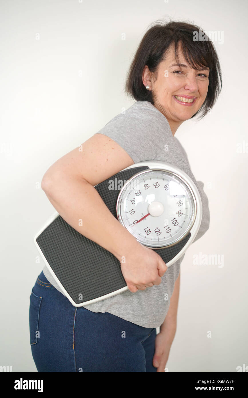 Overweight woman holding scale on white background Stock Photo - Alamy