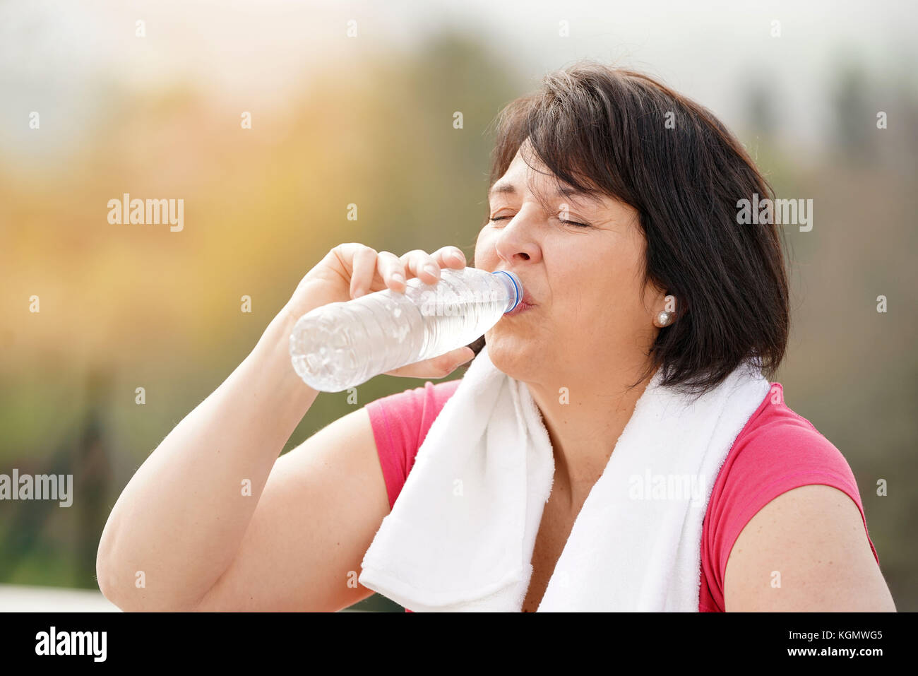 Overweight woman drinking water from bottle after exercising Stock ...