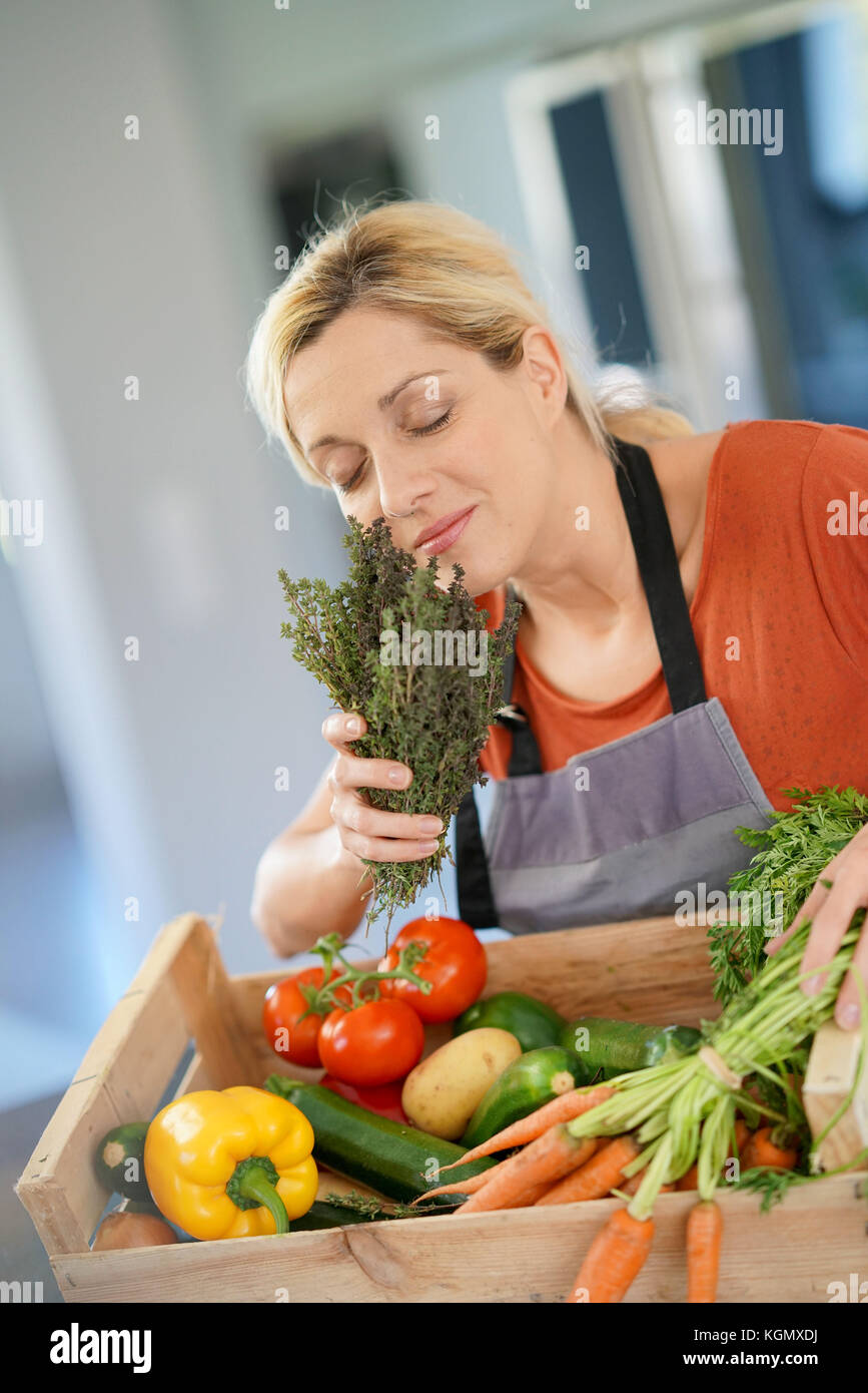 Portrait of woman in domestic kitchen holding basket of fresh ...