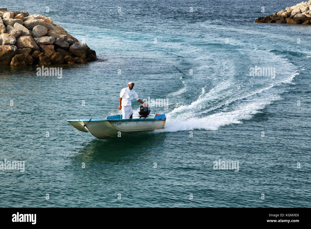 Man in traditional arabic thawb ride a speedboat near a coast in Oman ...
