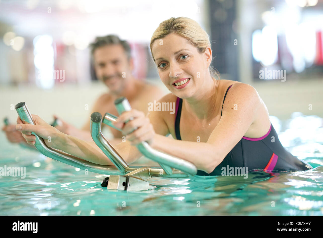 Couple in swimming-pool doing aquabike exercises Stock Photo - Alamy