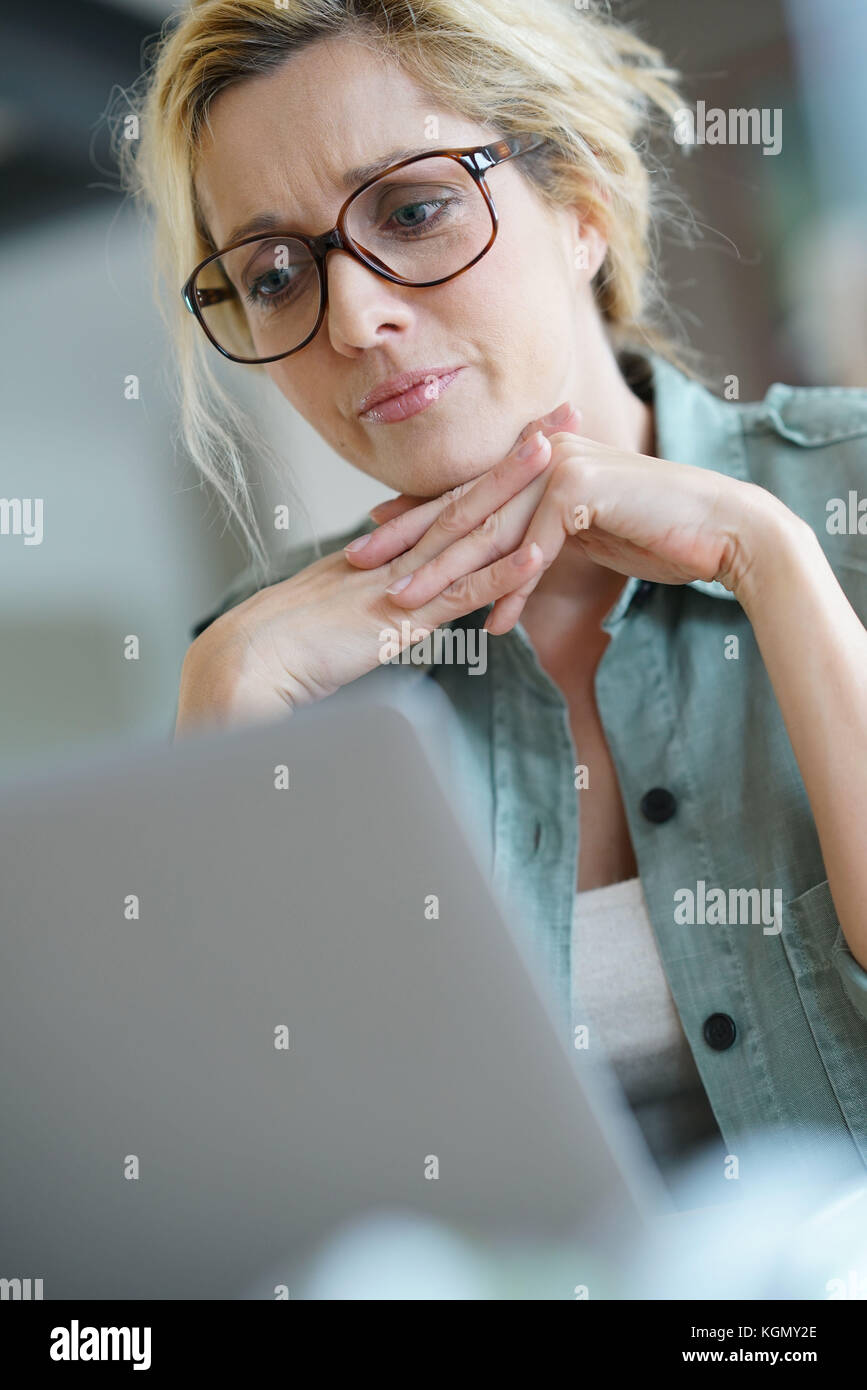 Portrait of blond woman working from home on laptop computer Stock ...
