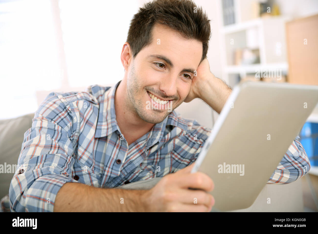 Cheerful handsome guy using tablet to read mail Stock Photo - Alamy
