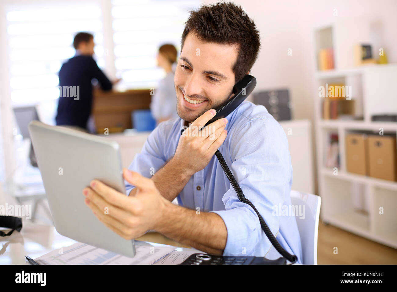 Cheerful man in office answering the phone Stock Photo - Alamy