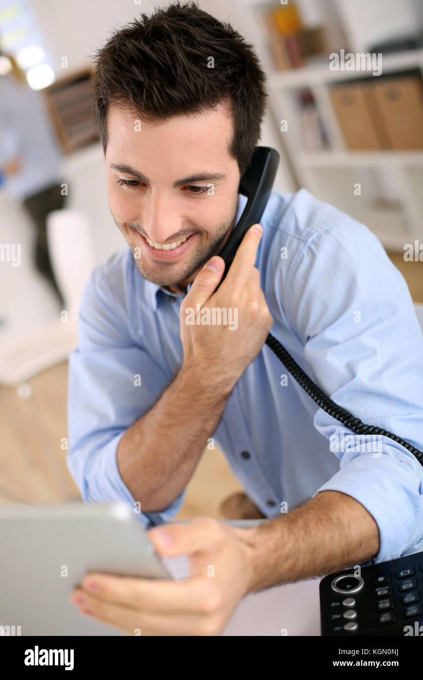 Cheerful man in office answering the phone Stock Photo - Alamy